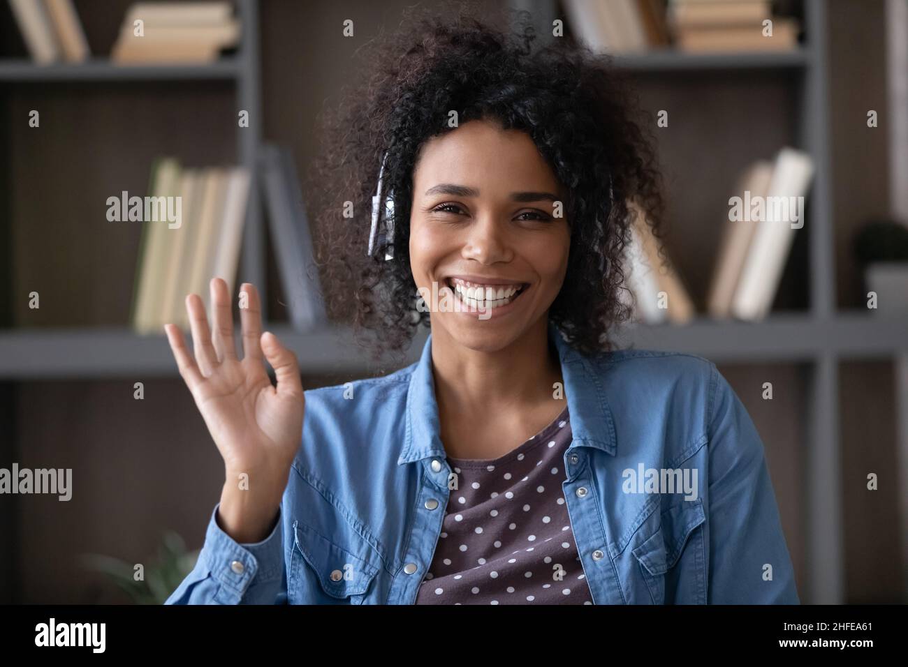 Happy African student, employee in wireless headphones waving hand ...