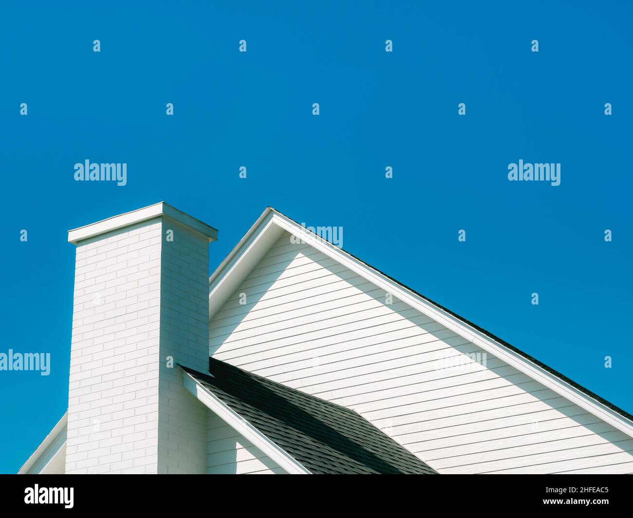 A white chimney bricks on the roof of the big wooden white house ...