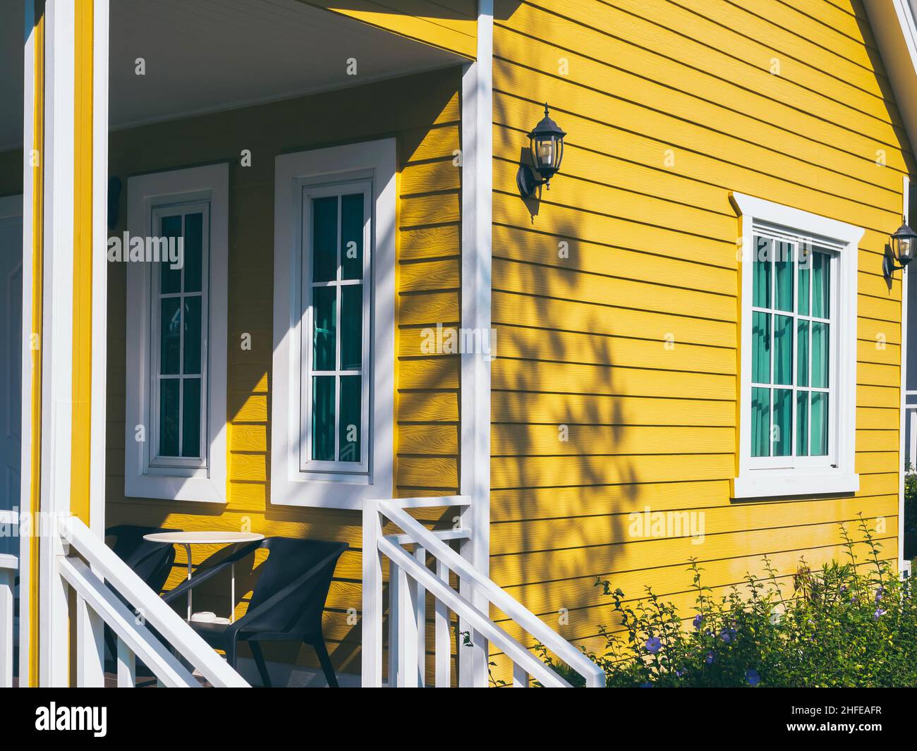 White closed windows at the yellow wooden cabin house with empty table ...