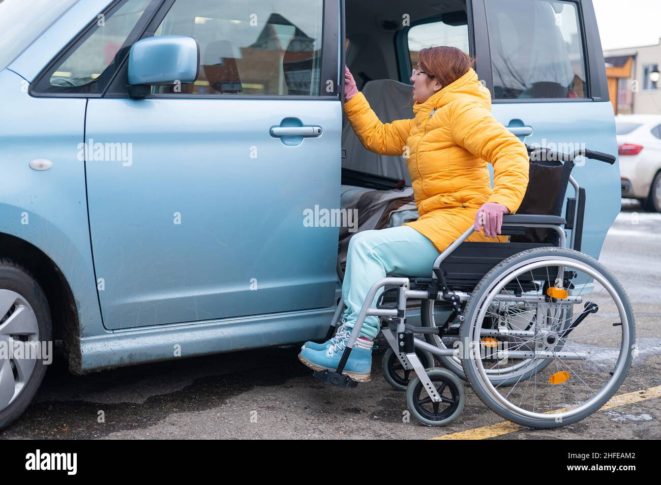 Caucasian woman in a wheelchair gets into the car Stock Photo - Alamy