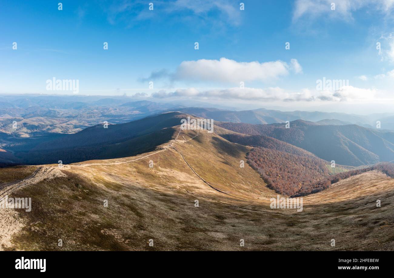 Narrow pathways among meadows on high mountain ridge under white fluffy ...