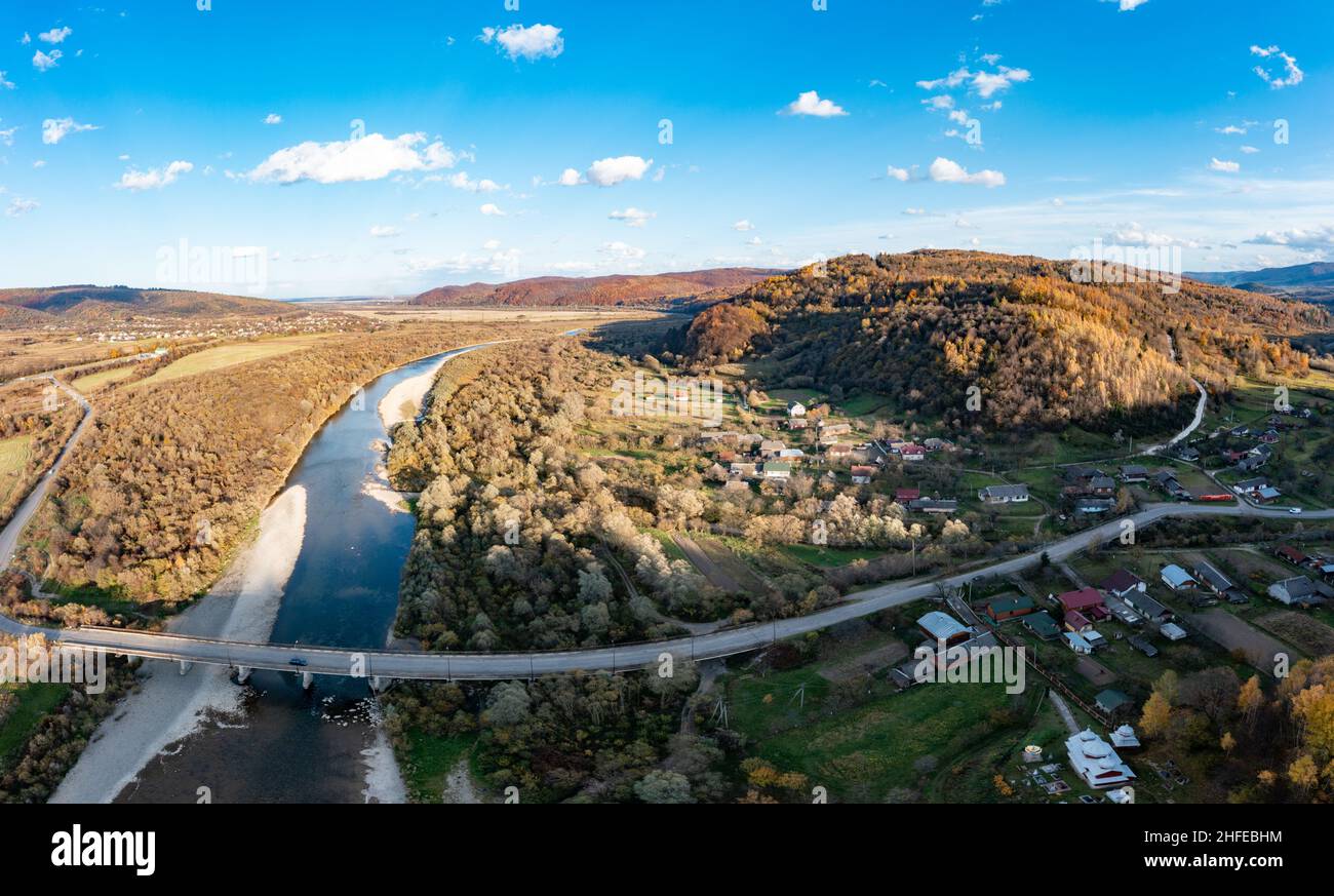 Bridge with asphalt road over narrow shallow river leading to ...