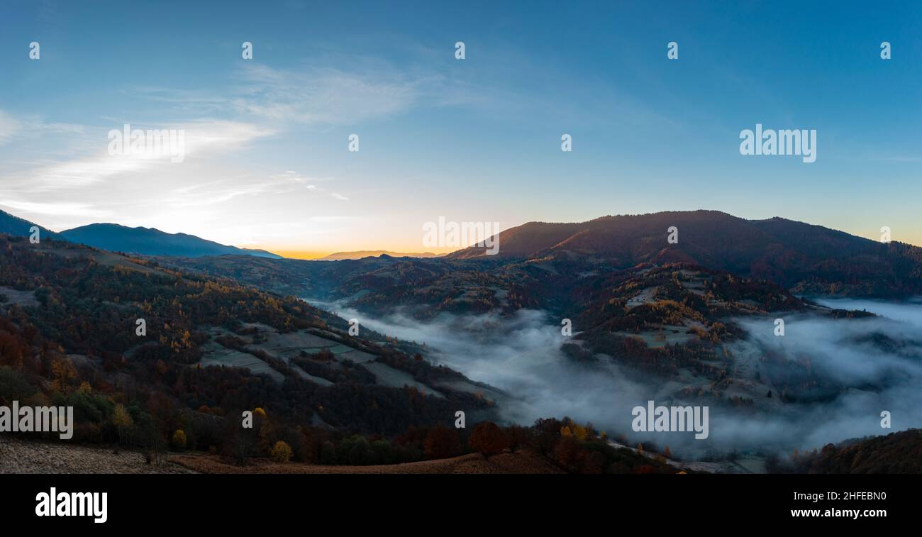 Thick fog among peaks of high mountain ridge covered with evergreen ...