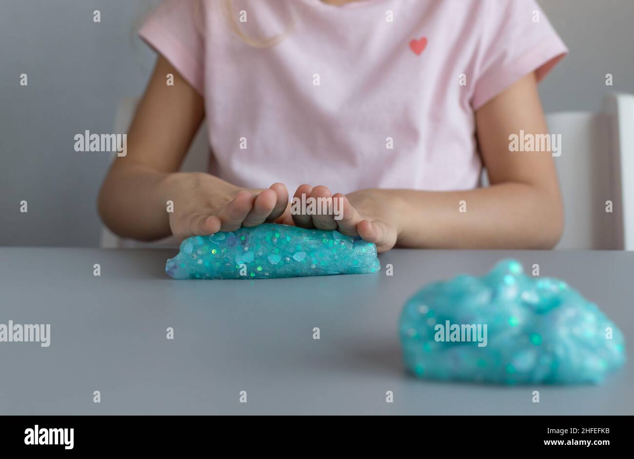 child playing with blue slime at gray desk Stock Photo - Alamy
