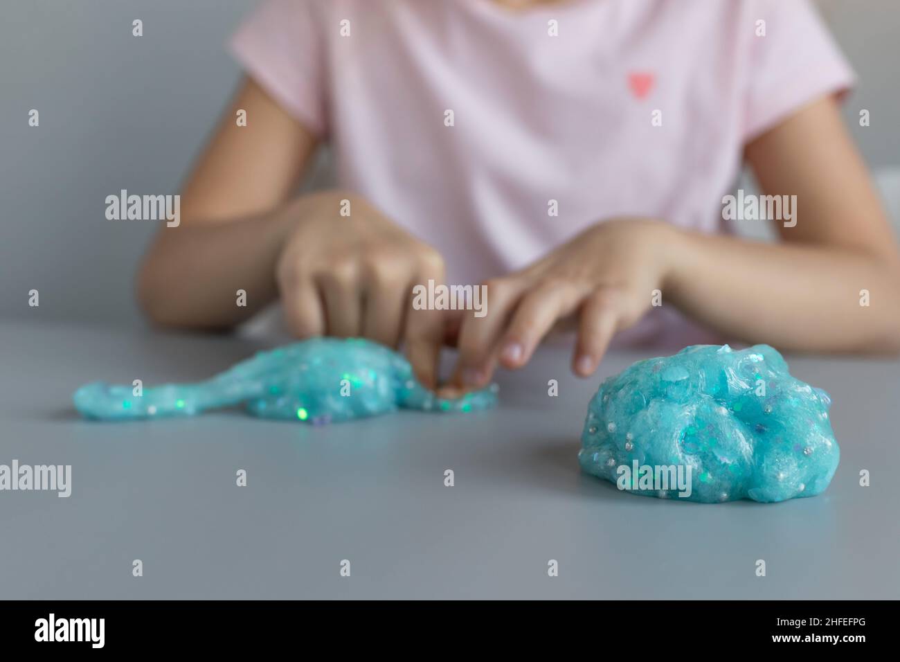 blue slime on gray desk and playing child in background Stock Photo - Alamy