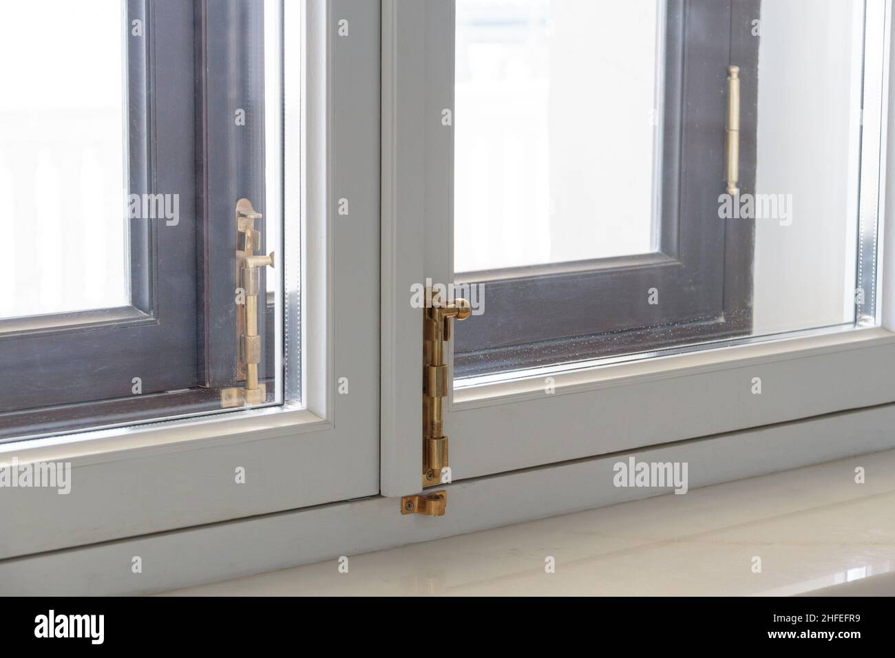 Close-up of a window frame. White modern plastic windows with golden ...