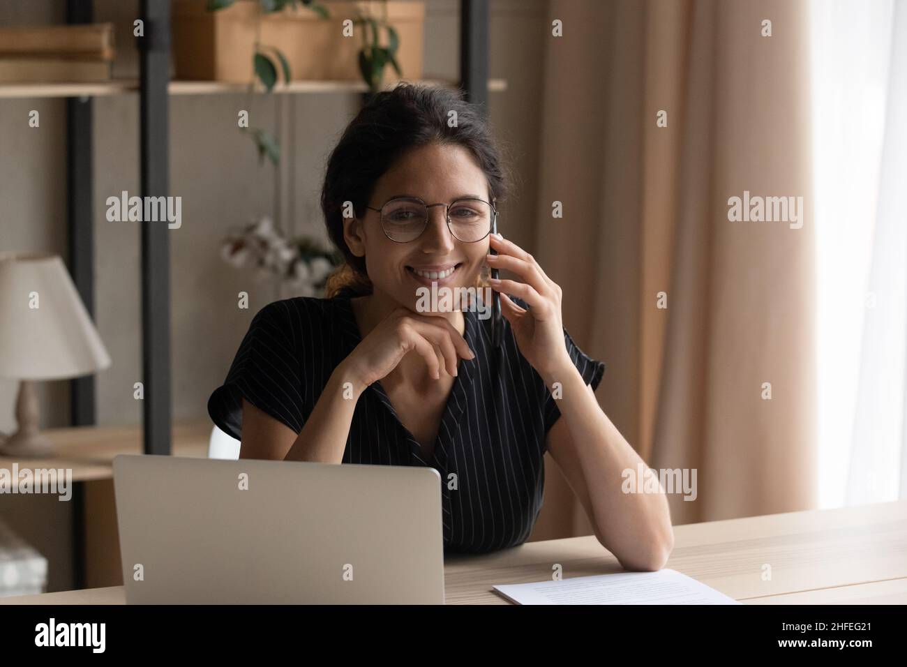 Smiling young pretty woman multitasking at home office Stock Photo - Alamy
