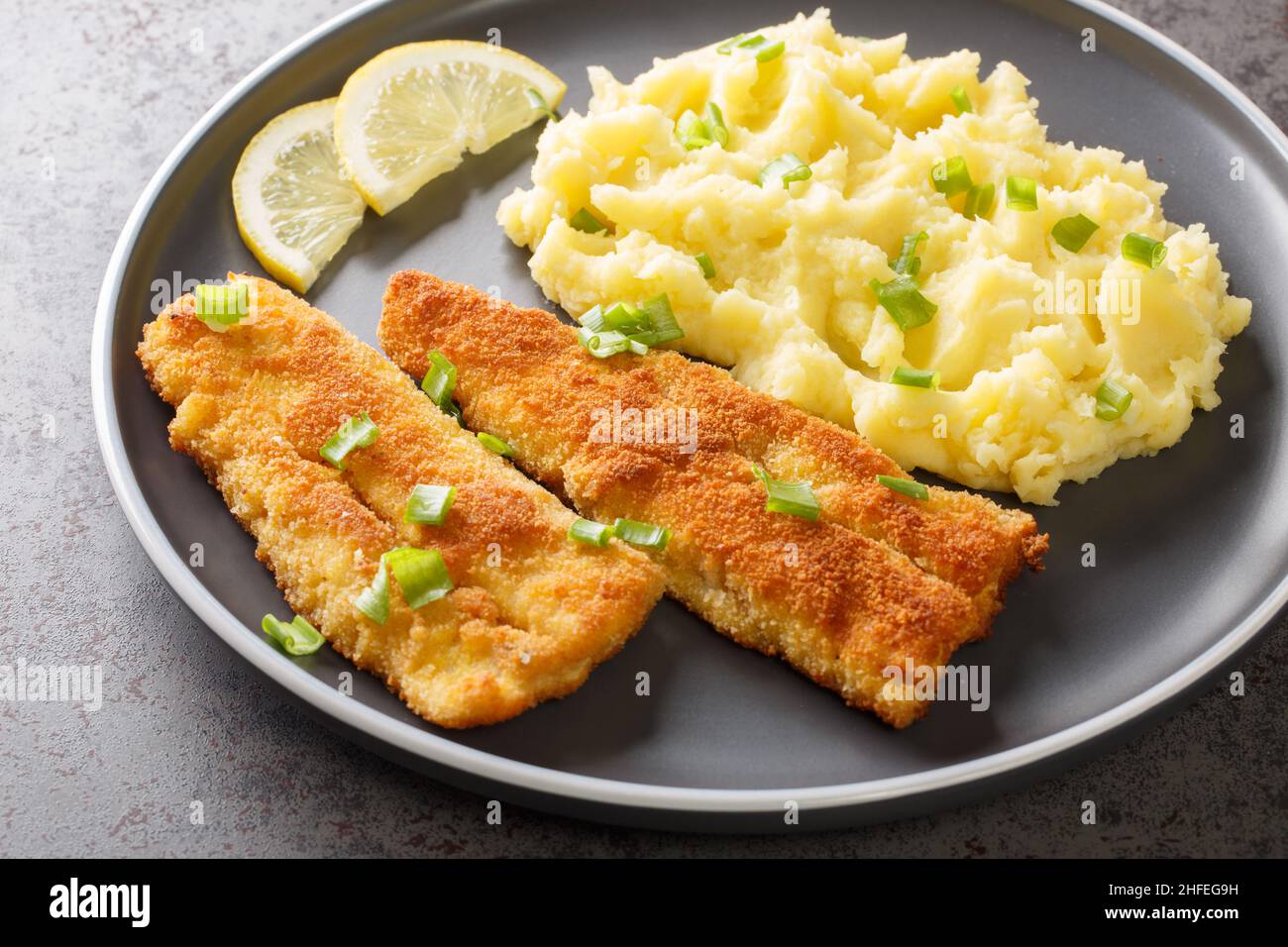 Hot dinner of fried sea fish and mashed potatoes close-up in a plate on ...