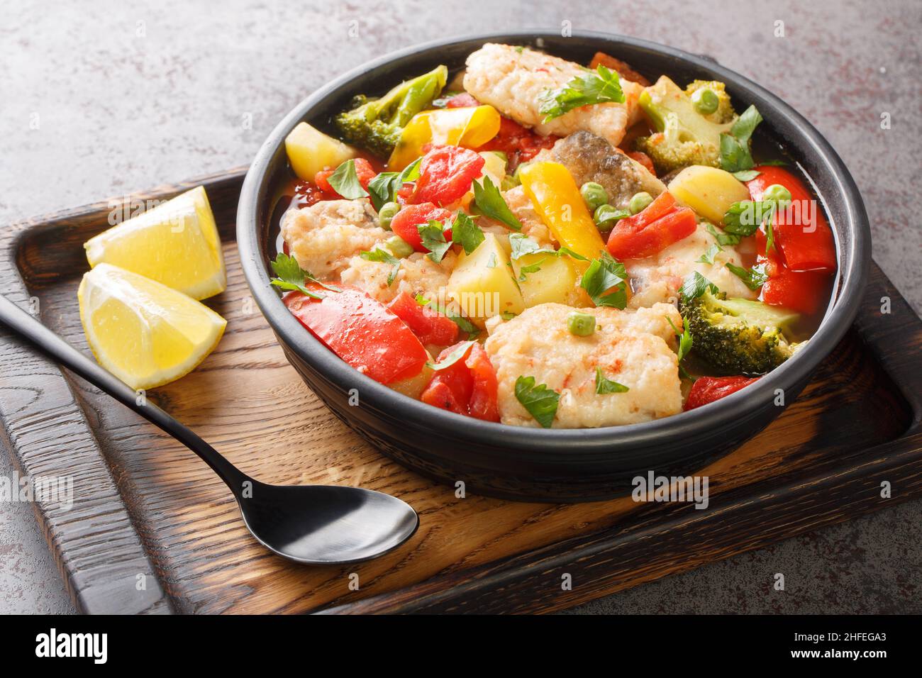 Delicious fish ragout with fresh summer vegetables close-up in a bowl ...