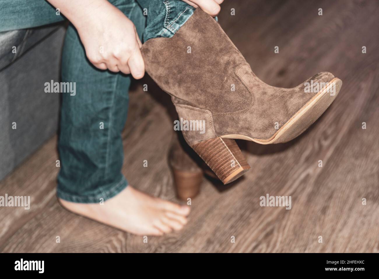 close-up. Shoe fitting. Female hands put on a boot on a leg. The girl ...