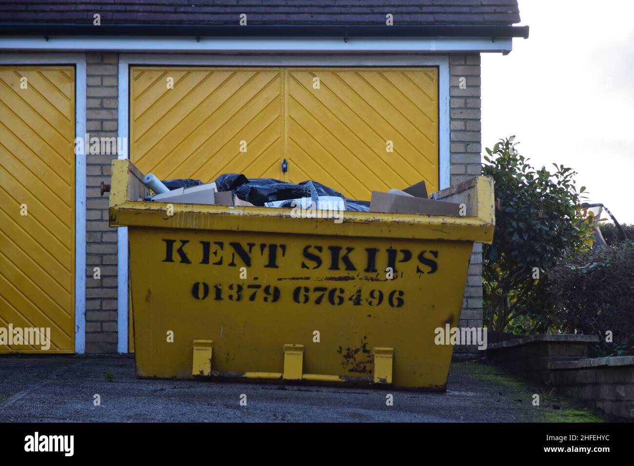 yellow skip outside yellow garage doors, suffolk, england Stock Photo ...