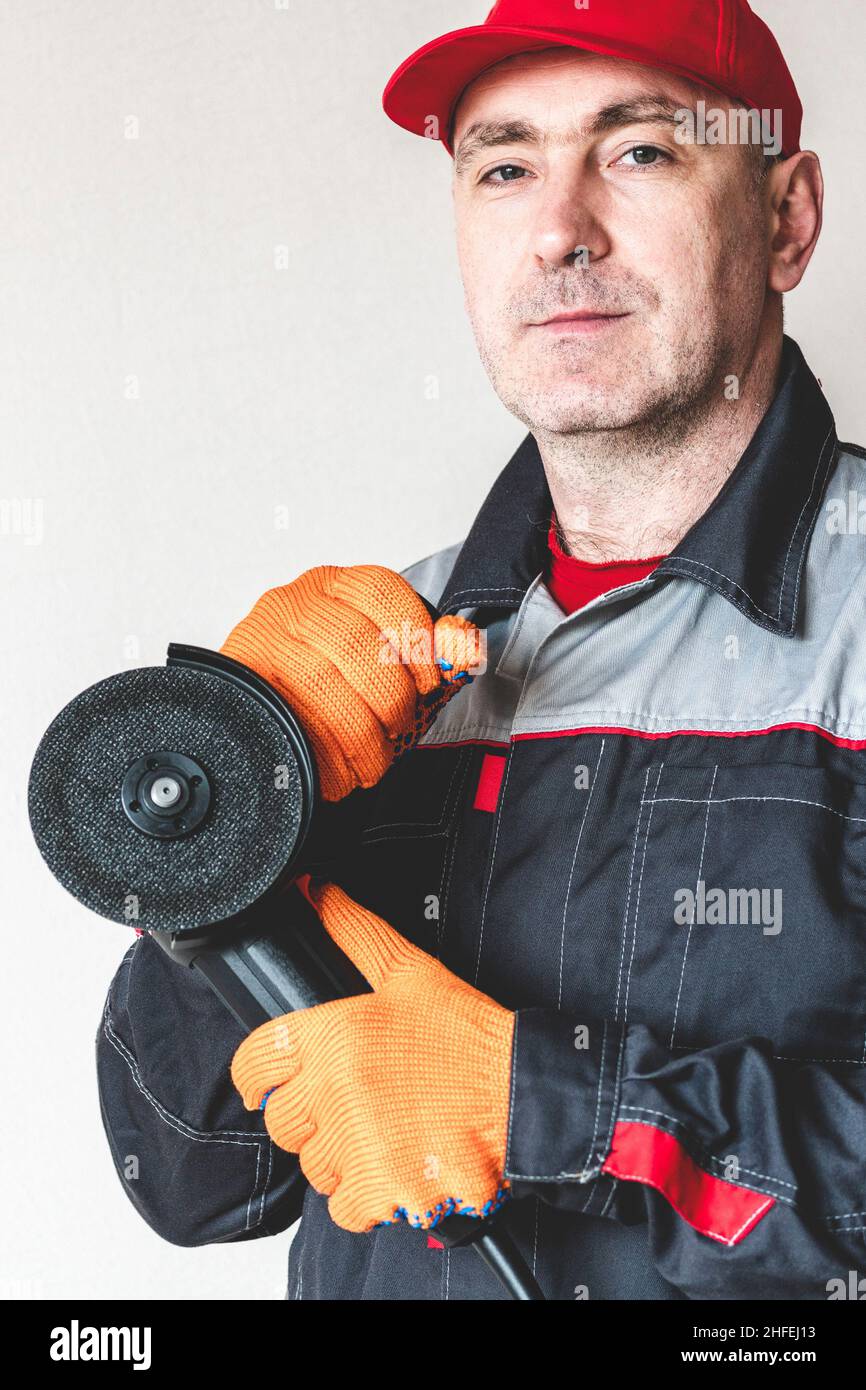 The worker is holding a grinding machine with a disk. Man in uniform ...