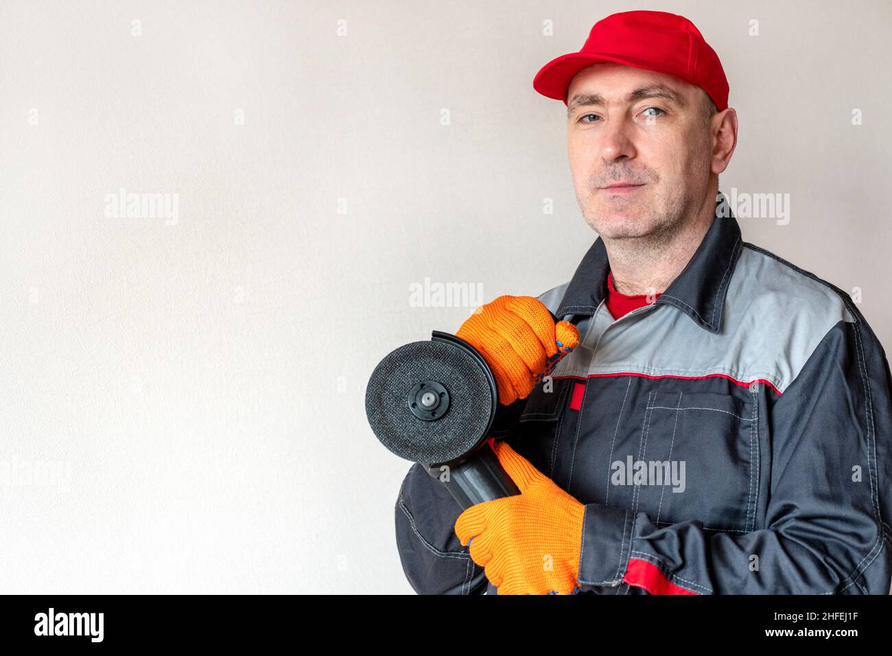 The worker is holding a grinding machine with a disk. Man in uniform ...