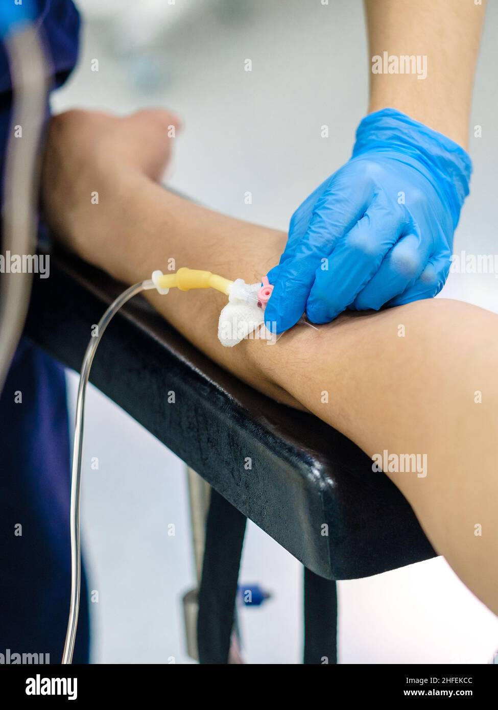 The doctor's hand in a sterile blue glove holds the dropper needle on ...