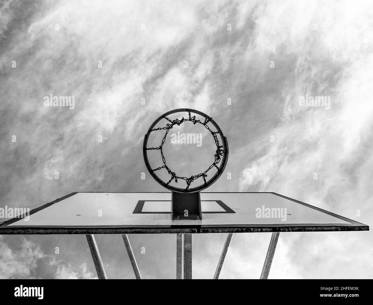 Basketball hoop and a cage with poor asphalt, sports background. BW ...
