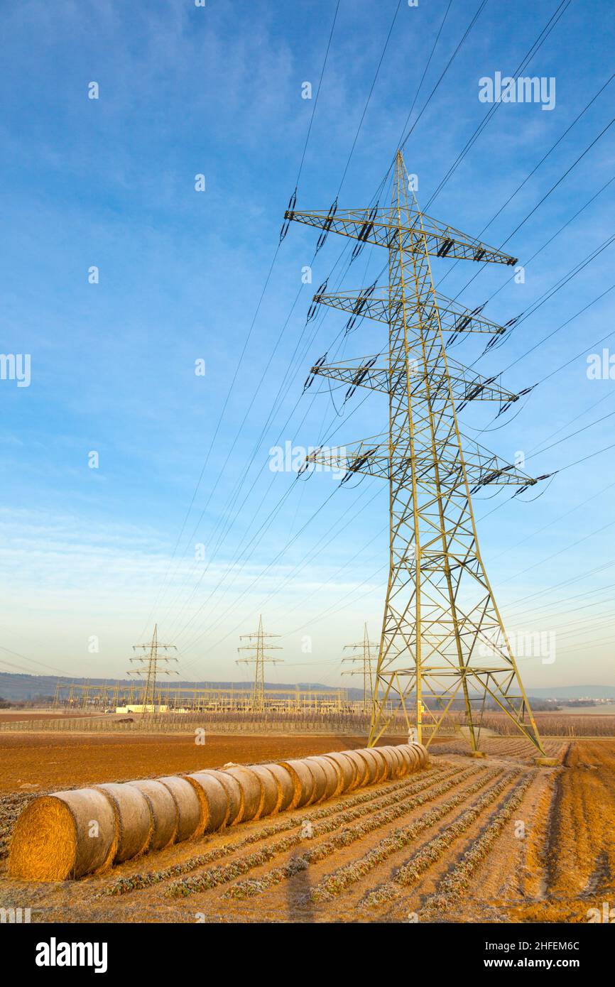 electrical tower in rural landscape with bale of straw Stock Photo - Alamy
