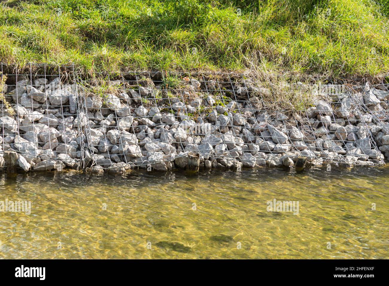 Fortification on the river bank. A stream bank with a stone gabion wall ...