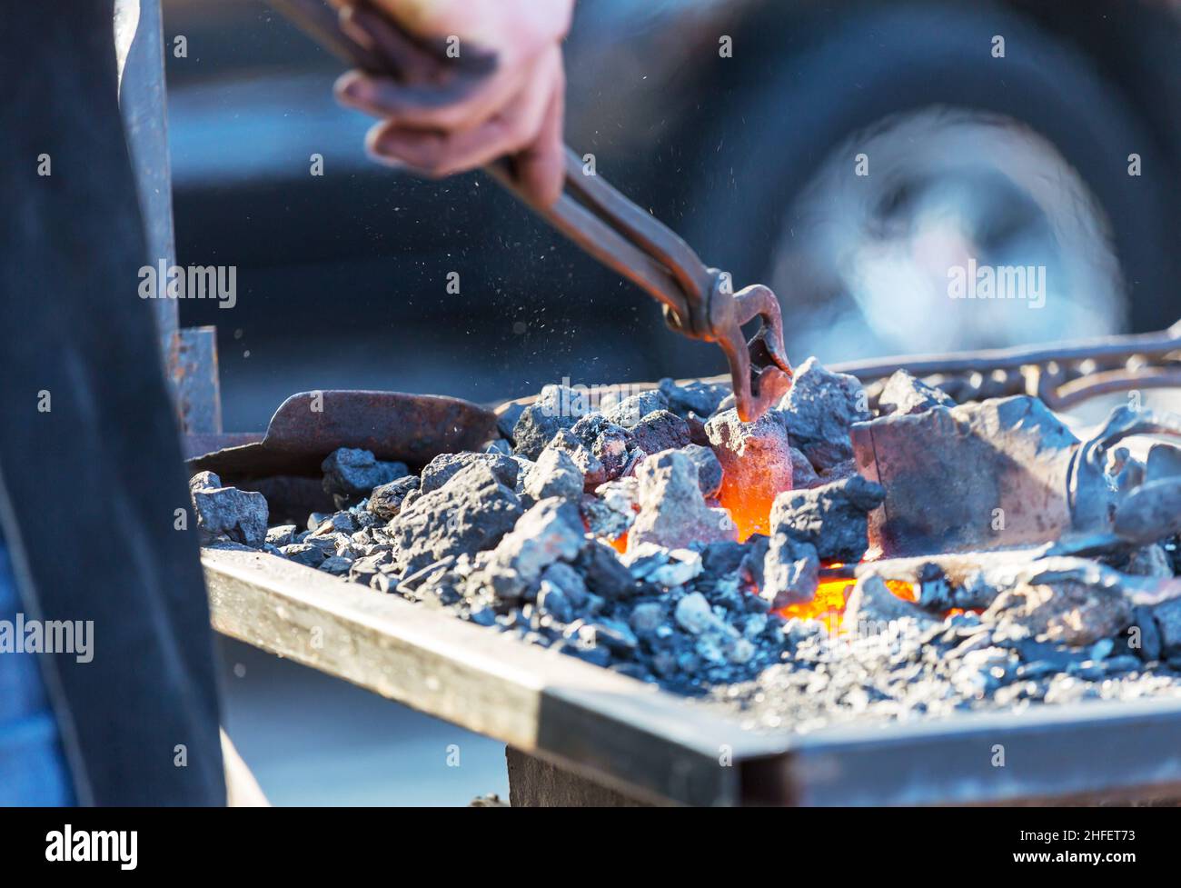 blacksmith hand holding tongs with metal piece and heating it in fire ...