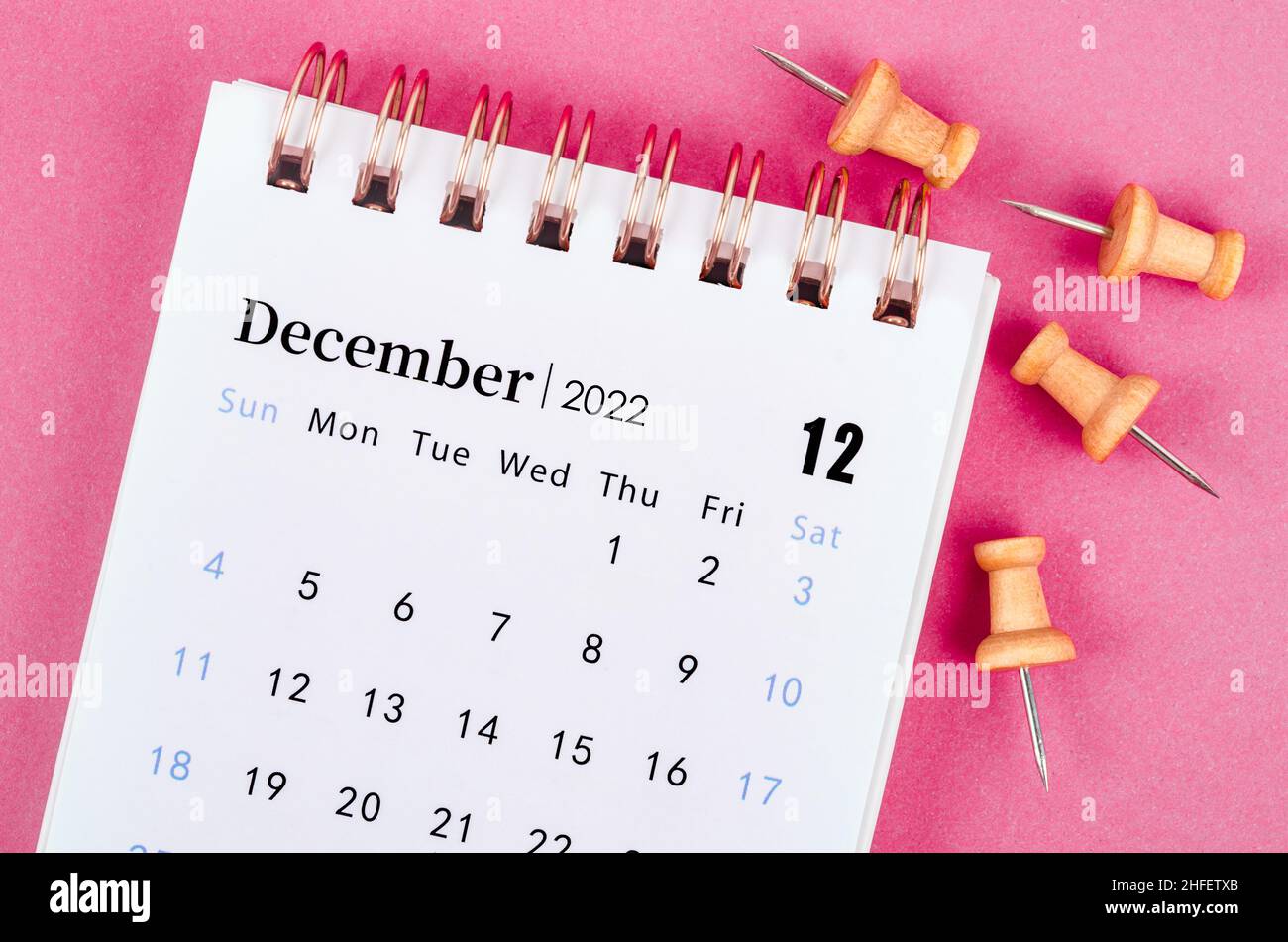 close up December 2022 desk calendar with wooden pin on pink background ...