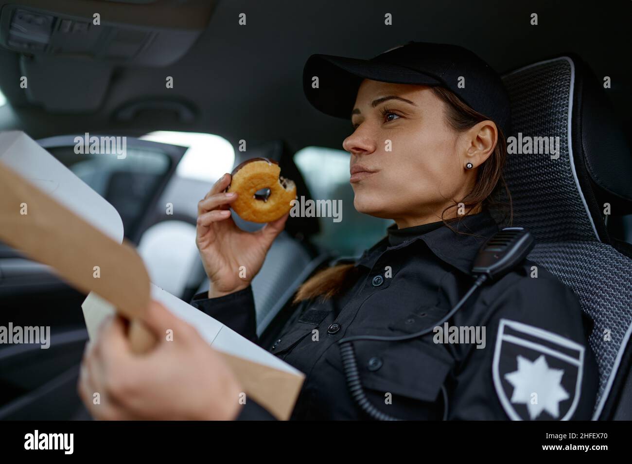 Woman police officer eating donut in car Stock Photo - Alamy