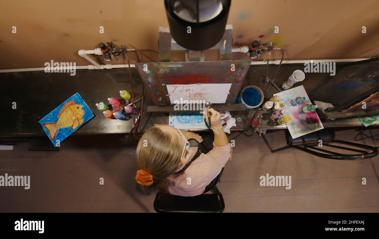 Woman artist learns to paint with airbrush with acrylic dye, paper and ...