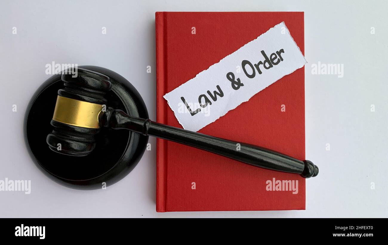Judge gavel with law and order text on torn paper on to of red book ...