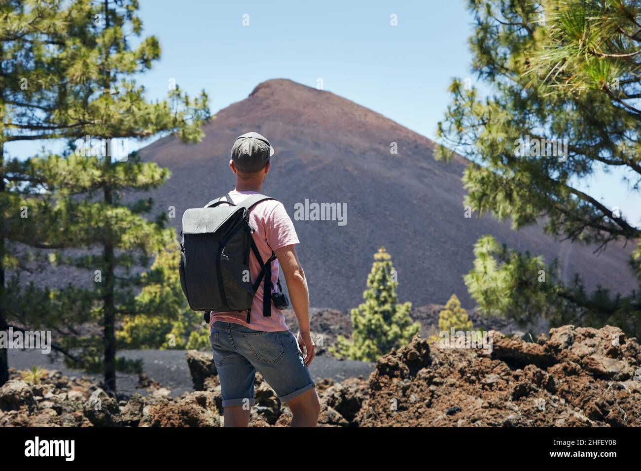 Traveler walking against volcanic landscape. Man with backpack looking ...