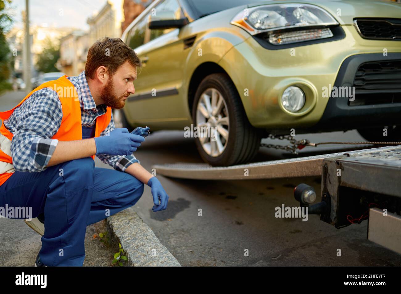 Male road worker monitoring car loading process Stock Photo - Alamy