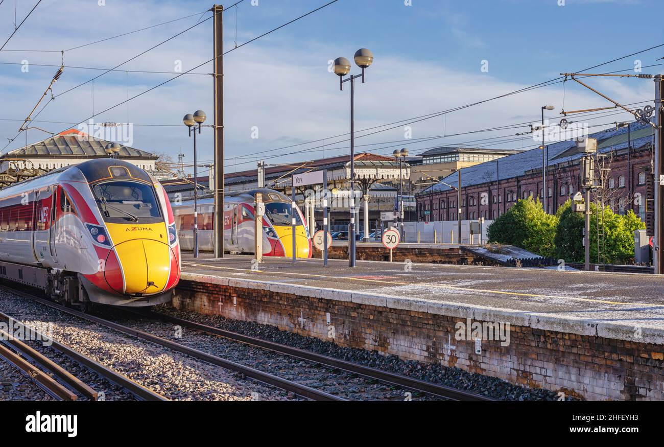 Two trains rest at a railway station platform with a light dusting of ...