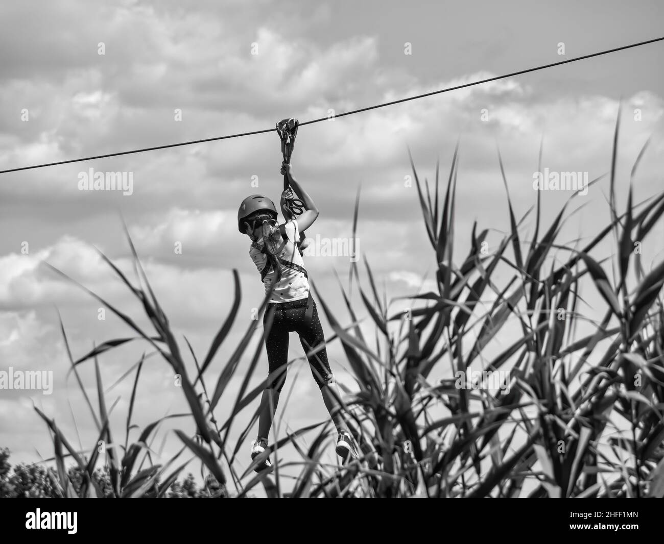 Back view with a teen young girl riding a zip line in Comana Adventure ...