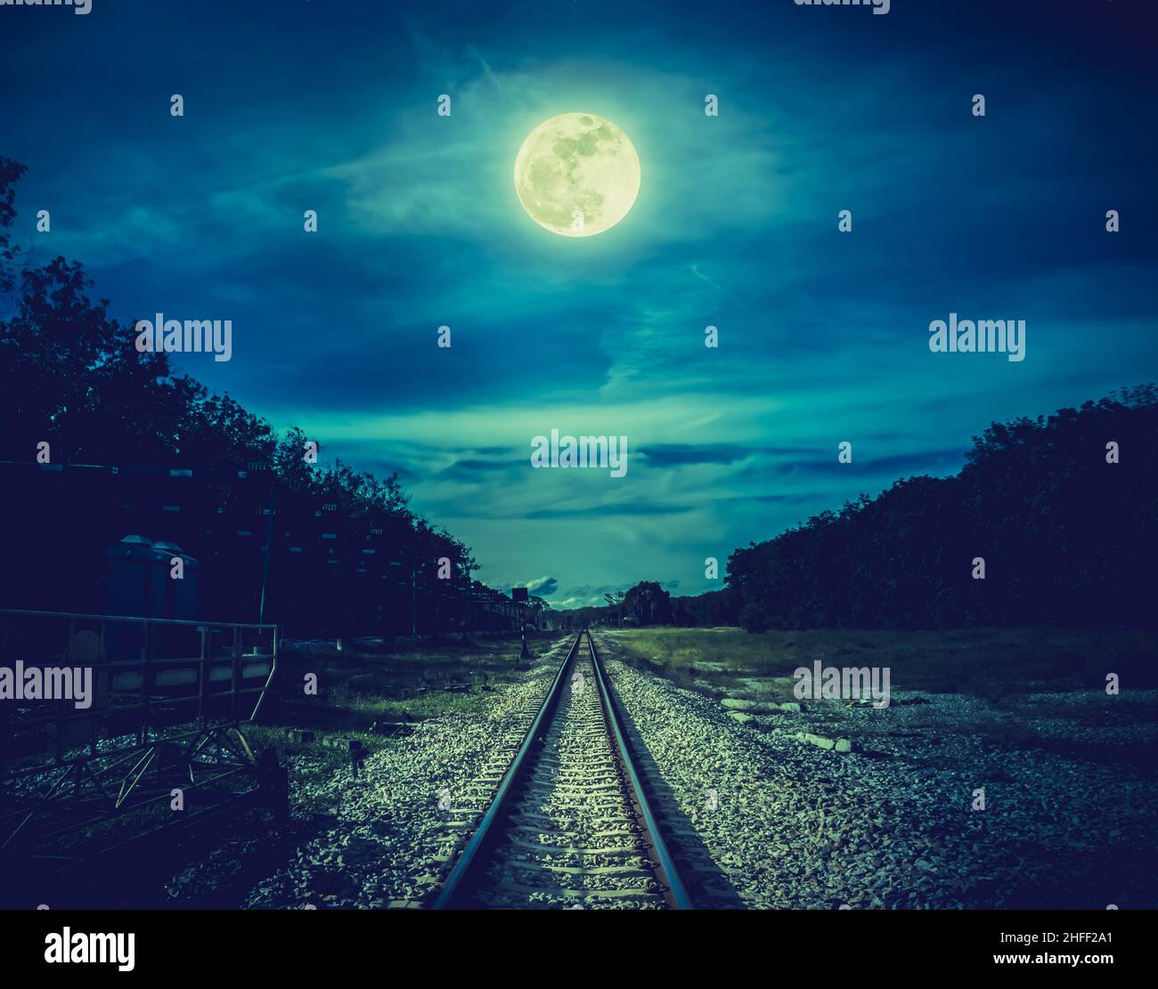 Railroad tracks through the woods at night. Beautiful sky and full moon ...
