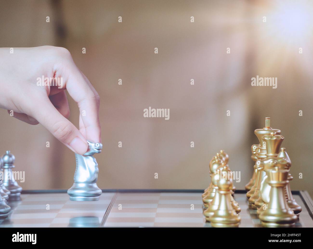 Hand businessman moving the golden knight chess fighting silver knight ...