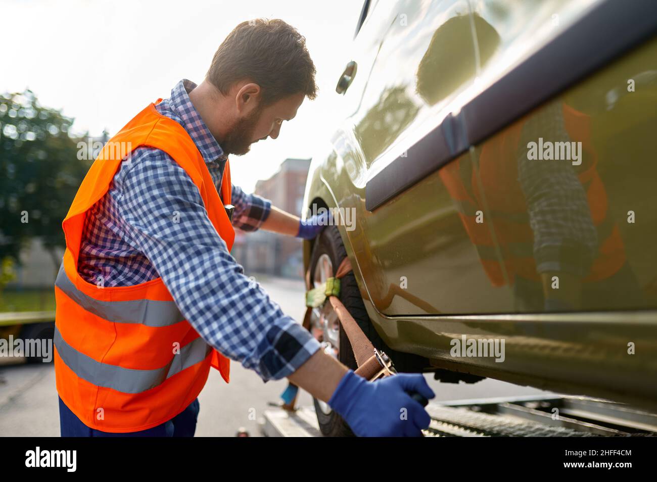 Tow truck operator fixing car on platform Stock Photo - Alamy