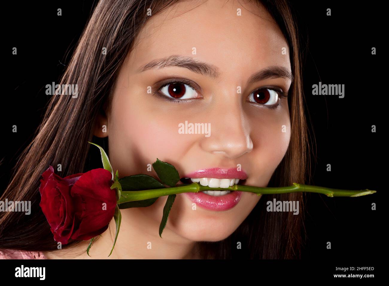 Pretty woman holding a red rose in her mouth Stock Photo - Alamy