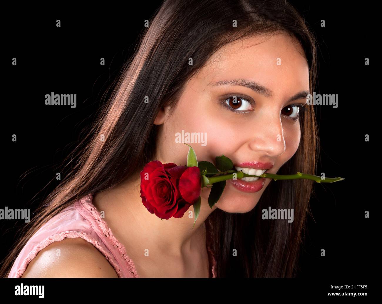 Beautiful brunette with a red rose between her teeth Stock Photo - Alamy