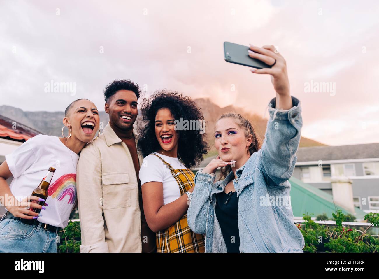 Friends taking a group selfie outdoors. Four happy friends posing for a ...