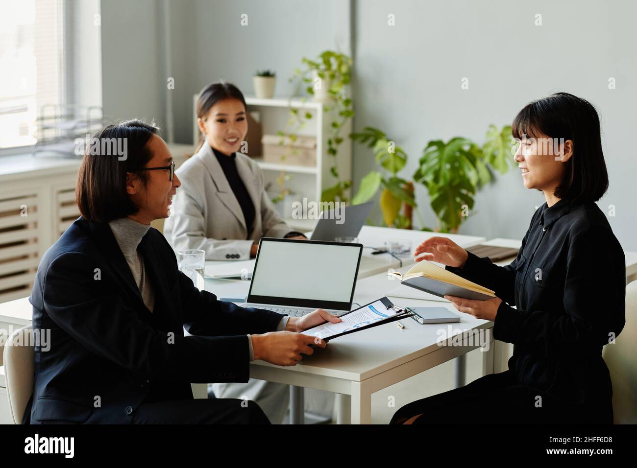 Side view at group of Asian business people discussing project during ...