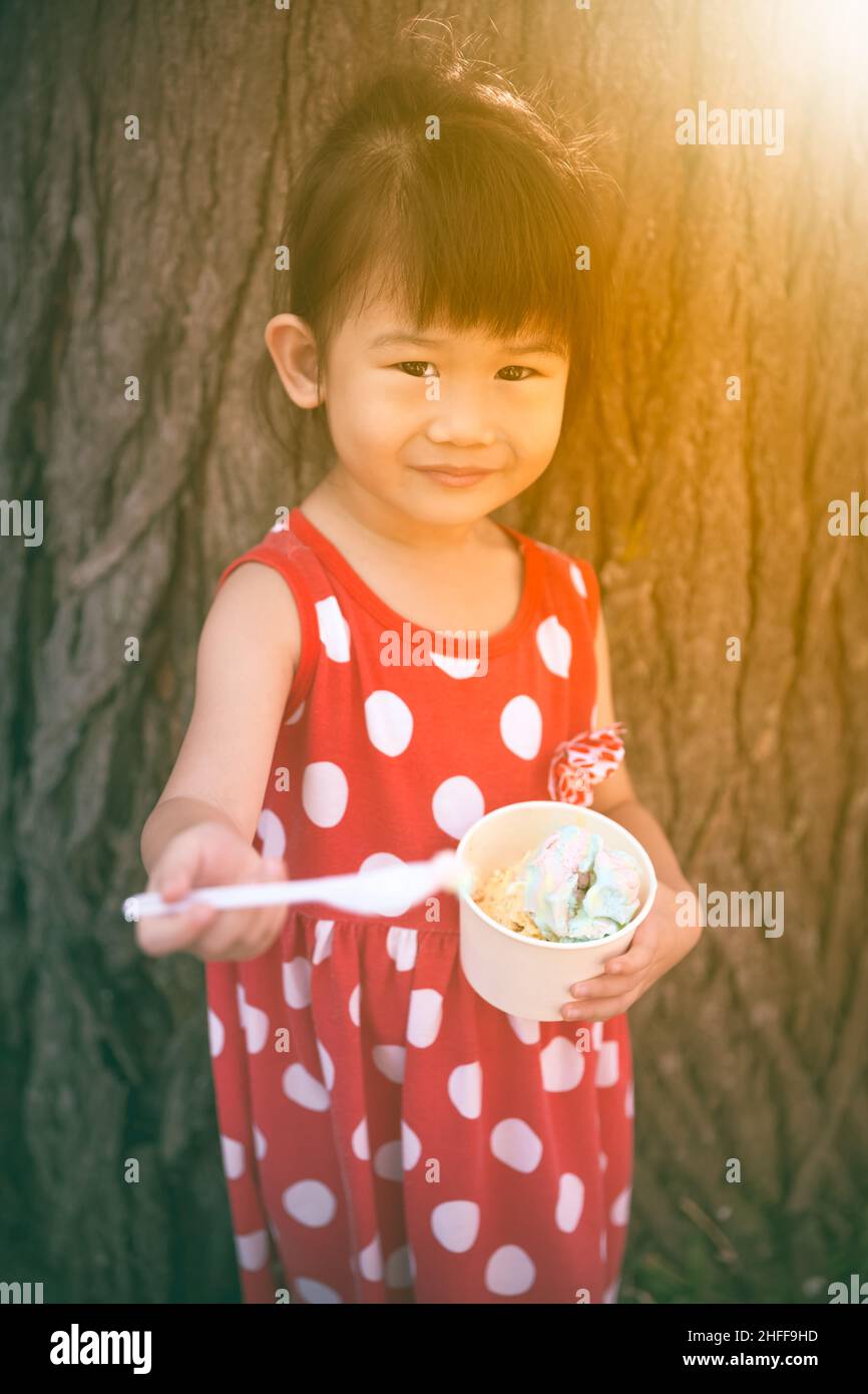 Adorable asian girl eating ice cream in the summer on vacation over a ...