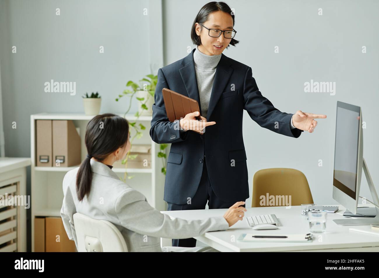 Portrait of Asian business person pointing at computer screen while ...