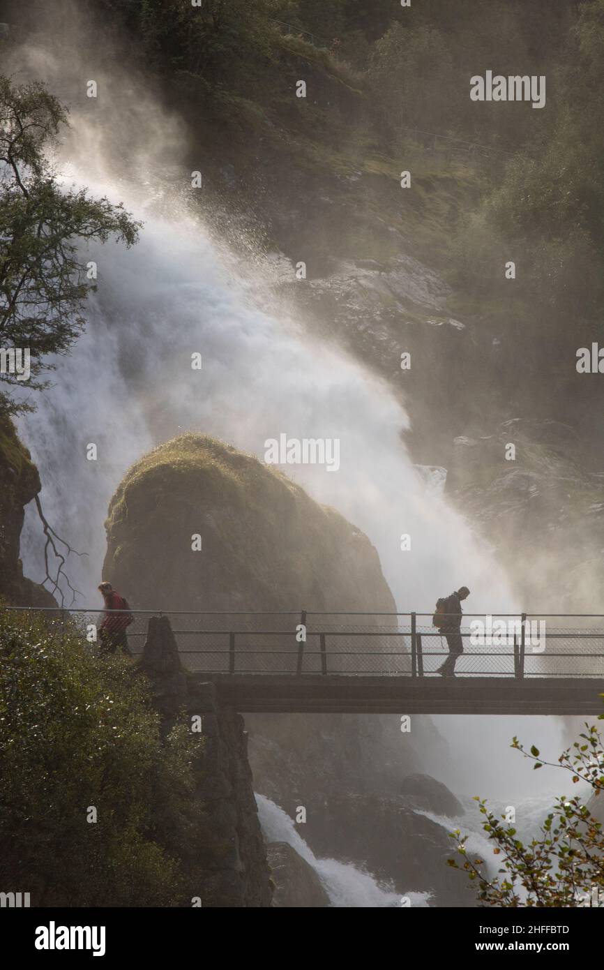 Misty landscape showing men walking on a bridge and a big waterfall ...