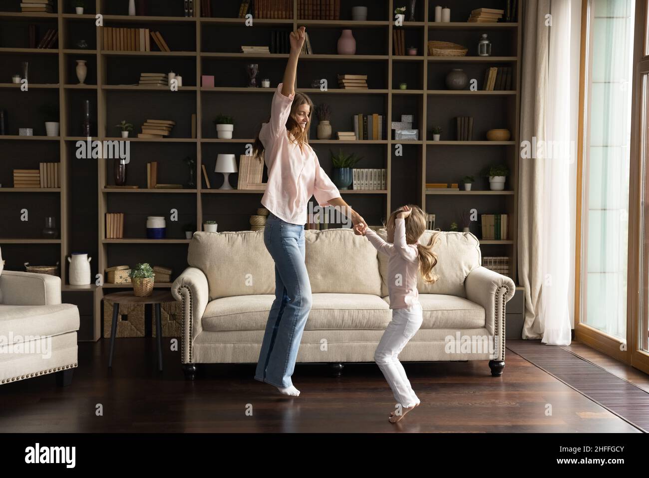 Happy mother and daughter dancing in living room Stock Photo - Alamy