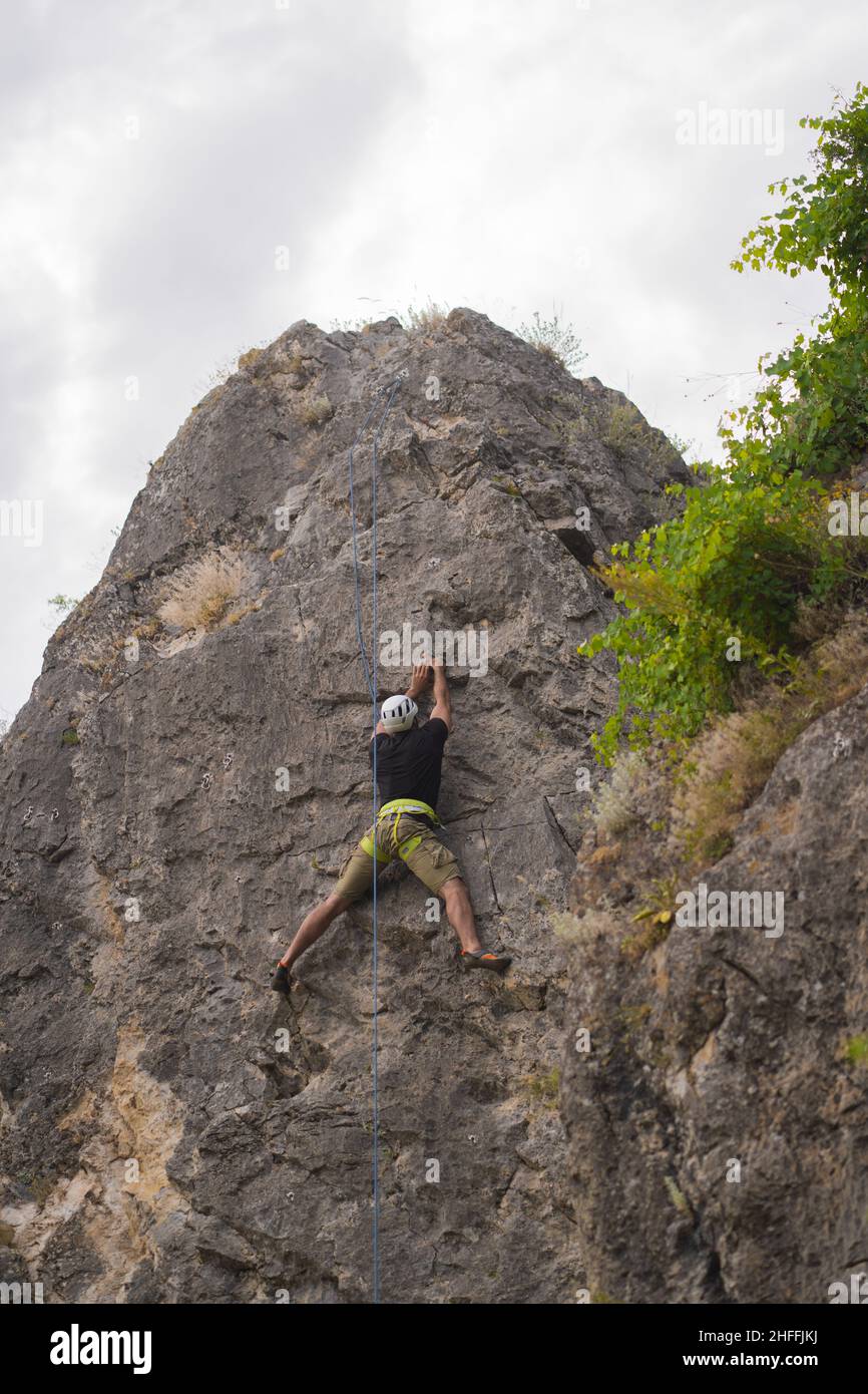 Handsome and fit guy is climbing the hill with the help of the rope ...