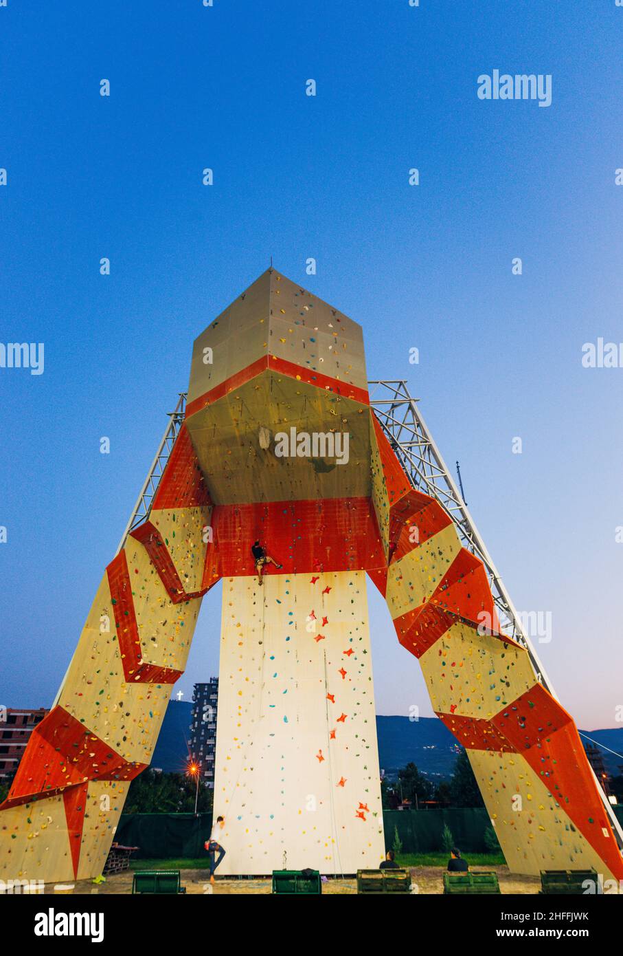 Man wearing belaying rope, climbing on a very high rock climbing wall ...