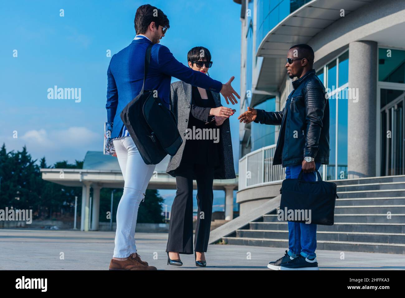 Business partners greeting one another by shaking hands outside ...