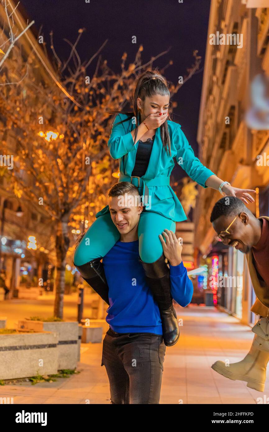 Two multiracial couples are doing a piggyback ride together and ...