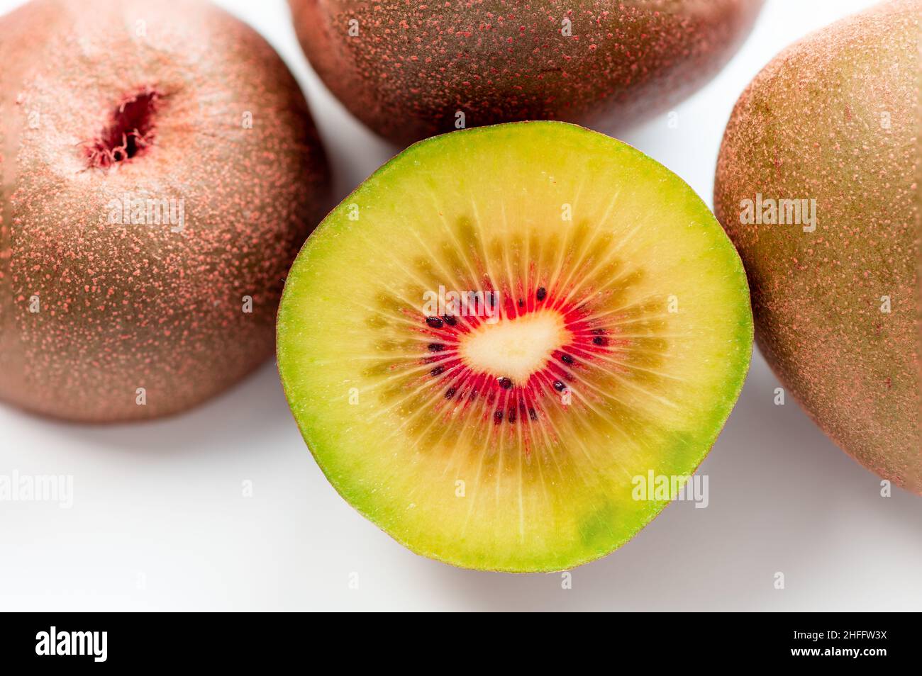 Red kiwi fruit berry half with three other kiwiw on white background ...