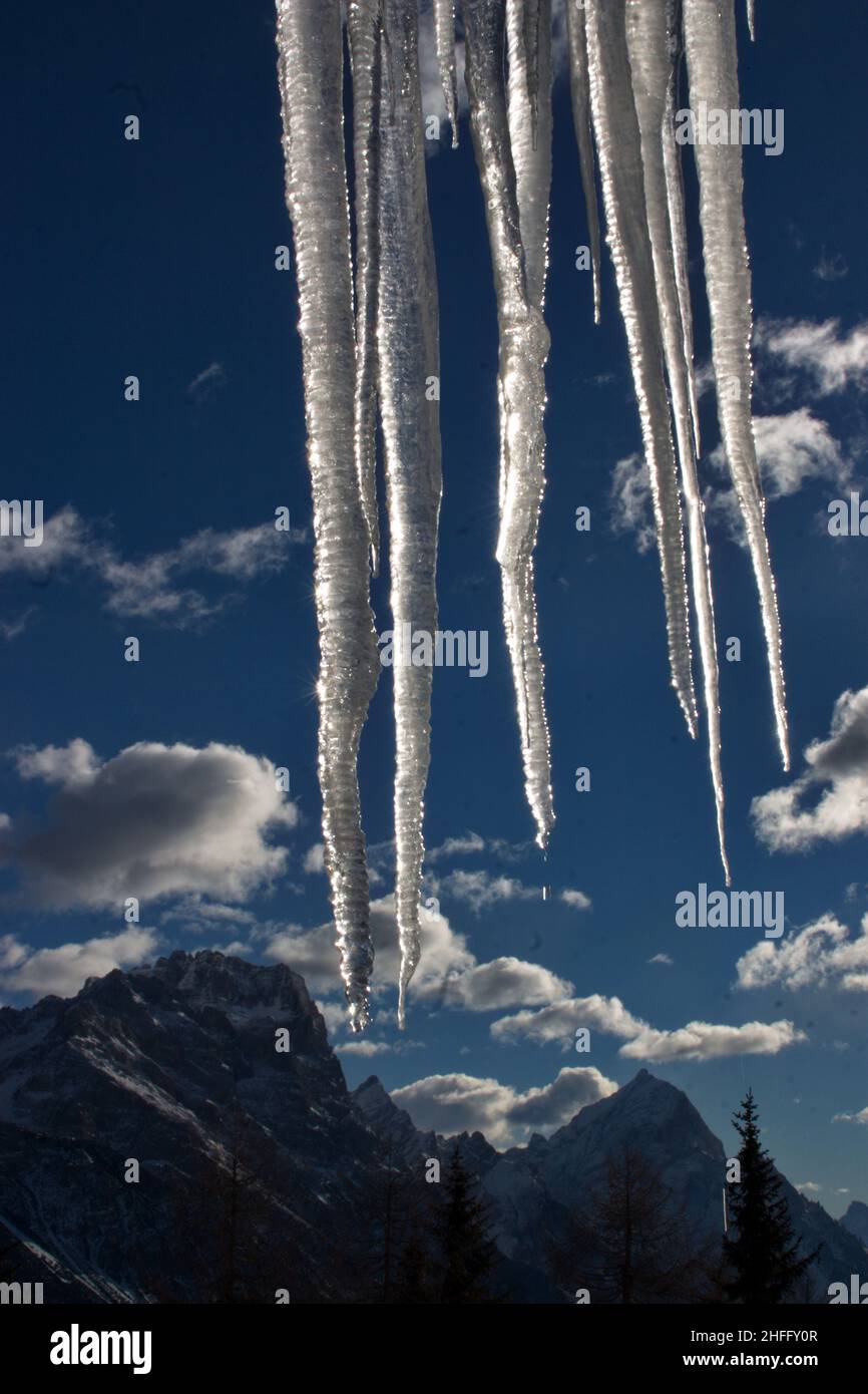 Icicl with mountains in the background.es formation hanging from a roof ...