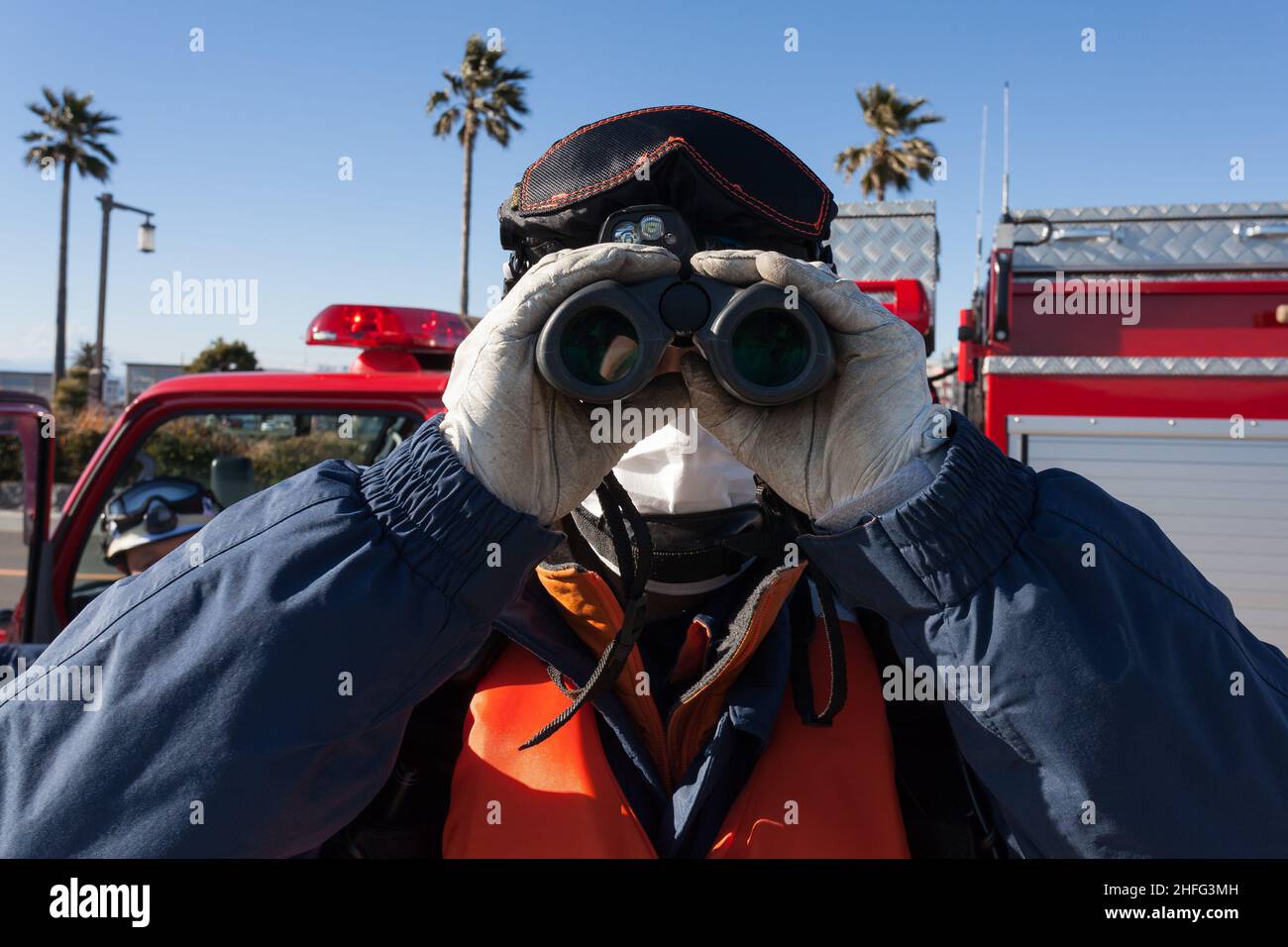 A local firefighter keeps watch for further tsunamis by a fire truck at ...