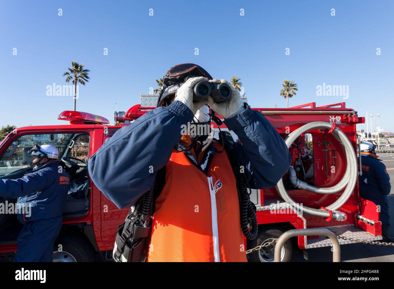 A local firefighter keeps watch for further tsunamis by a fire truck at ...