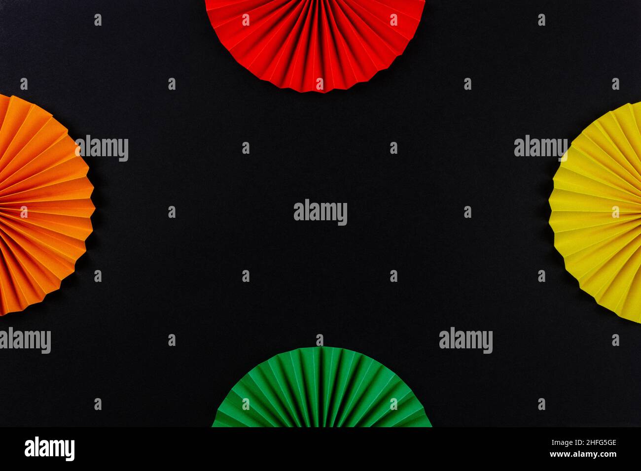 Red, orange, yellow and green color paper origami flowers on the black ...